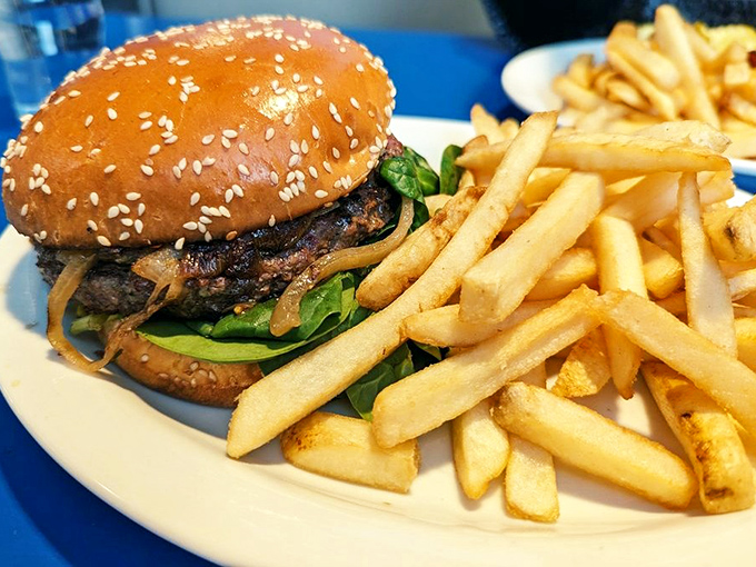 A burger that requires a strategy to eat. The sesame-studded bun barely contains its contents while those fries stand at attention, ready for duty.