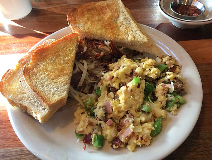 Toast so perfectly golden it belongs in Fort Knox, alongside scrambled eggs studded with colorful veggies and a side of nostalgia.
