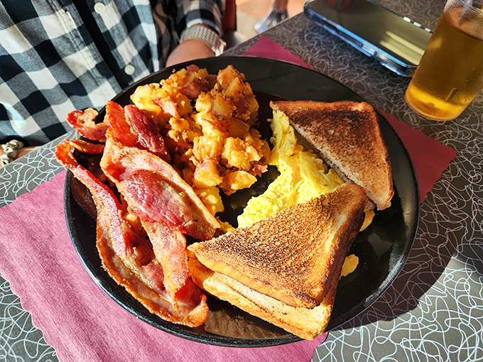 The breakfast plate that launched a thousand road trips: perfectly cooked eggs, crispy bacon, golden toast, and home fries that make hash browns nervous.