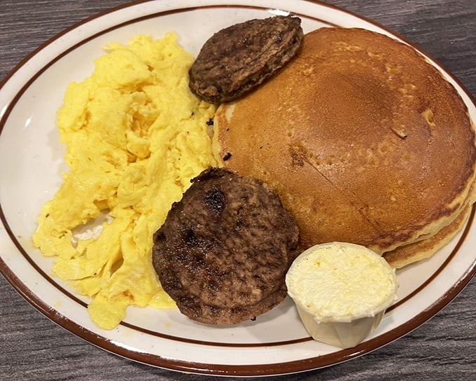 The breakfast trifecta: fluffy scrambled eggs, perfectly grilled sausage patties, and a pancake the size of a frisbee. Morning glory on a plate.