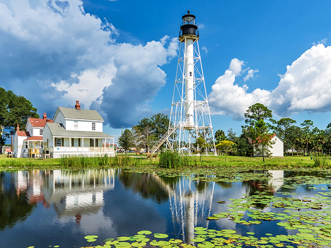 The Cape San Blas Lighthouse stands tall against a perfect blue sky, its reflection dancing in lily-pad waters like something straight from a Florida tourism dream.