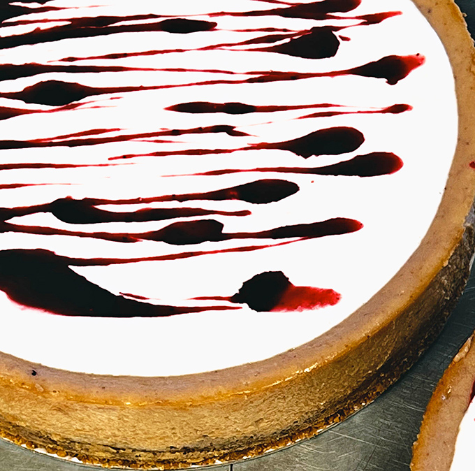 A cheesecake that's dressed to impress with dramatic raspberry streaks – like abstract art you can devour with a fork.