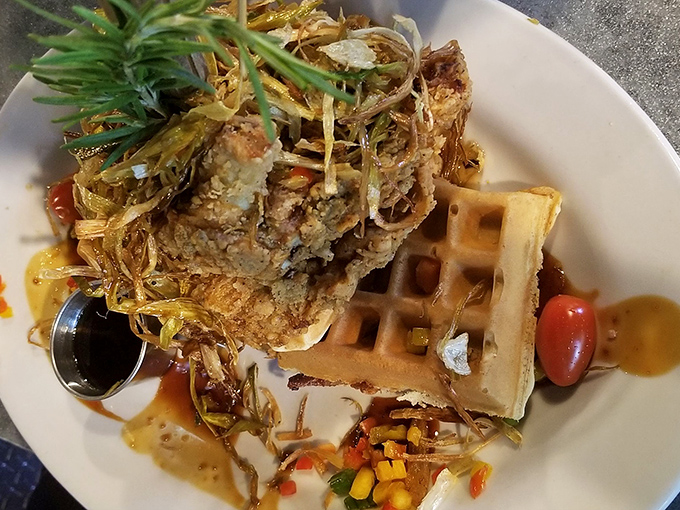 The famous chicken and waffles tower defies both gravity and reasonable portion sizes. That rosemary sprig isn't garnish—it's a structural support beam.