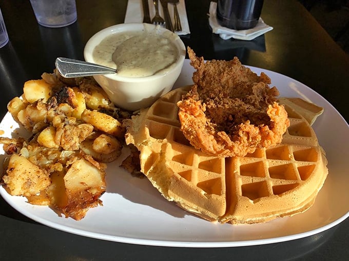 Southern comfort meets breakfast bliss: crispy chicken perched atop a golden waffle with potatoes on the side&mdash;because one carb is never enough.