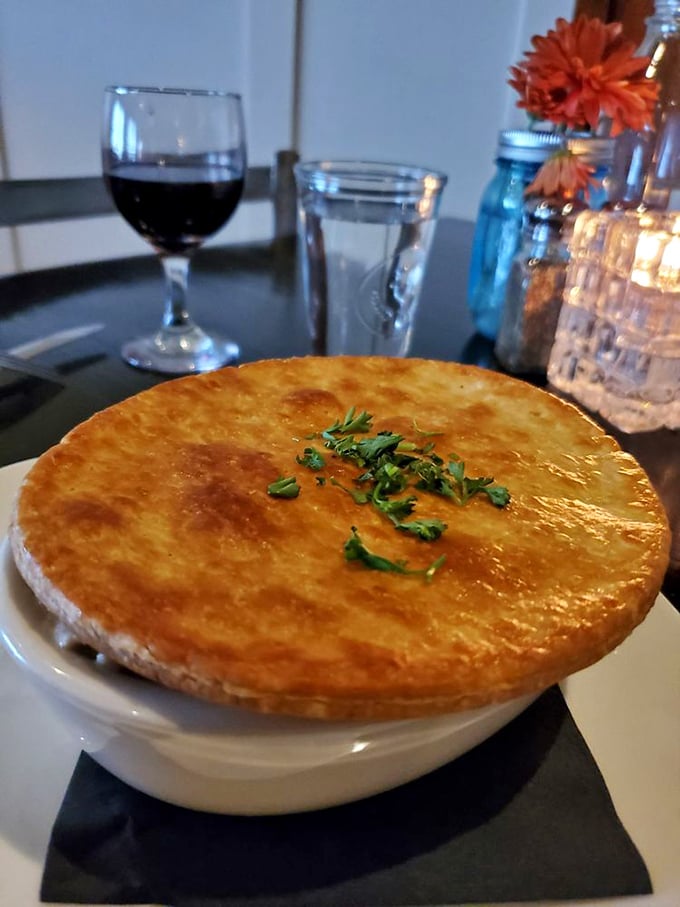 This chicken pot pie wears a golden crown of pastry that shatters with your fork, revealing a steaming treasure of comfort below.