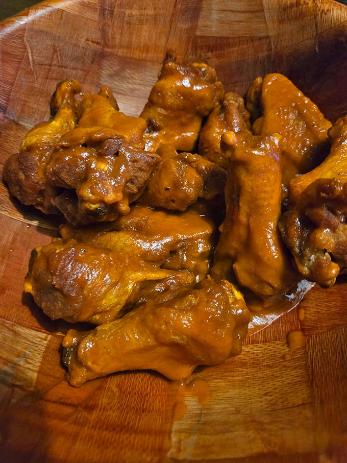 Wings so saucy they should come with their own rain poncho. That wooden bowl isn't just serving&mdash;it's containing a flavor explosion.