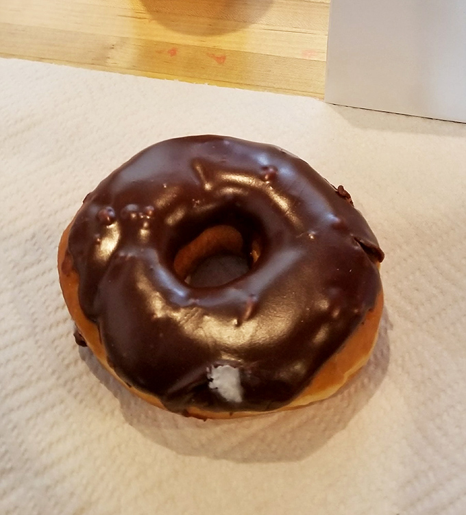 A chocolate glazed donut catches light like a diamond and shatters with similar satisfaction. This one's ready for its close-up.