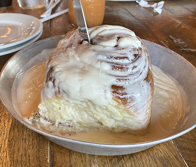 A cinnamon roll so massive it needs its own area code, drowning in glaze like it should be.