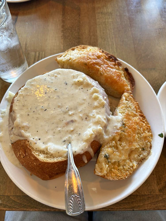 Behold the holy grail of chowder experiences &ndash; creamy, herb-flecked perfection nestled in a sourdough throne with golden garlic bread standing guard.
