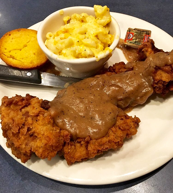 Country fried steak smothered in gravy that could make a vegetarian question their life choices, with cornbread and mac & cheese standing by.