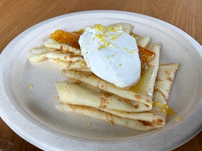These crepes, delicate as silk scarves, cradle their fillings while that dollop of cream melts languidly like it's on vacation in the French Riviera.