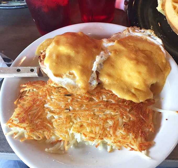 Eggs Benedict that would make a French chef weep with joy, perched atop a throne of hash browns worthy of breakfast royalty.