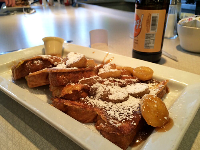 Thick-cut French toast with caramelized bananas and powdered sugar creating the kind of breakfast that ruins all other breakfasts.