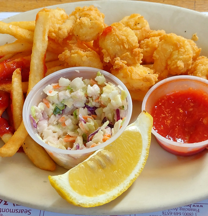 Plump fried shrimp nestled beside crispy fries, with coleslaw and cocktail sauce standing by&mdash;a plate that whispers "vacation" with every bite.
