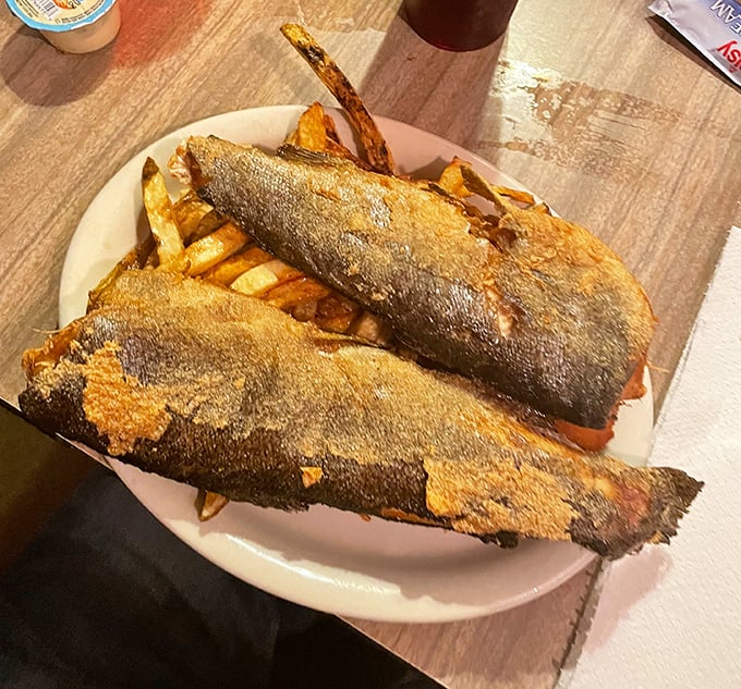The famous rainbow trout arrives golden and crispy, perched atop a bed of fries like mountain royalty taking its rightful throne.