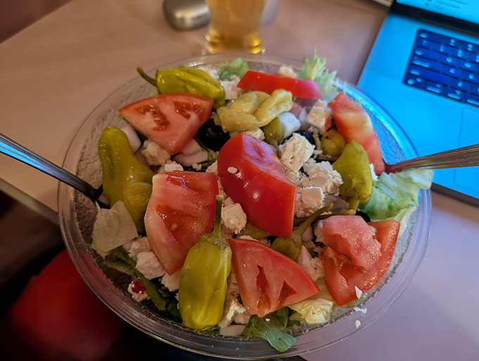 The Greek salad arrives like a Mediterranean vacation on a plate—feta, pepperoncini, and tomatoes having their own little party.