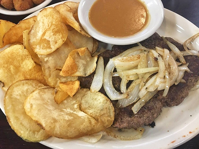 A hamburger steak smothered in onions with homemade chips that proves simple food, done right, is the ultimate luxury in our complicated world.