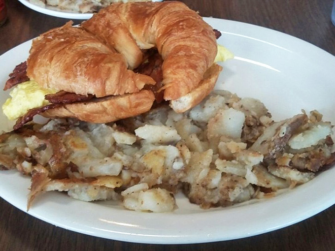 The humble croissant sandwich, elevated to breakfast royalty with golden eggs and those home fries that deserve their own fan club.