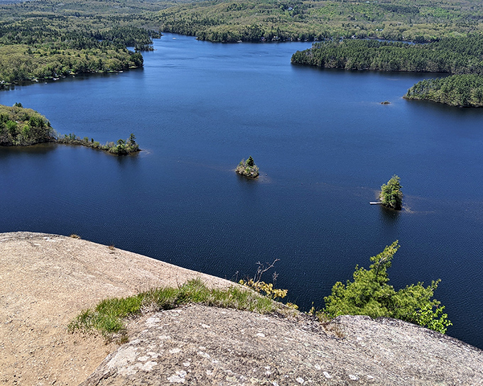 From Maiden Cliff's rocky perch, the lake below sparkles like a sapphire set in Maine's emerald forest ring.