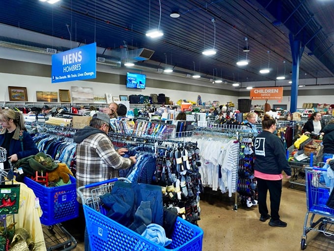 The bustling men's department offers everything from casual tees to office attire. Blue signs overhead guide shoppers through this sea of possibilities.