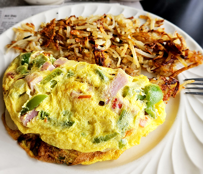 An omelet that's practically bursting with ham and peppers, paired with hash browns so perfectly crispy they deserve their own fan club.
