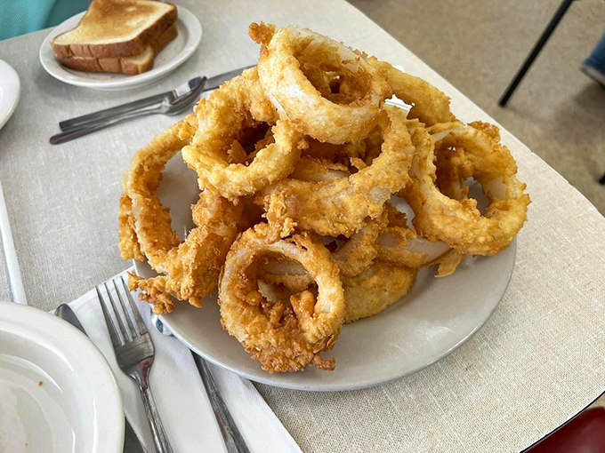 Onion rings stacked like edible Olympic rings—crispy, golden-brown halos that make you forget vegetables are supposed to be good for you.