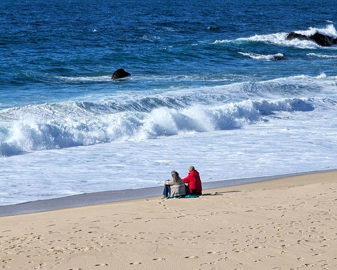 Front-row seats to nature's greatest show. Two beachgoers find the perfect spot to contemplate life's big questions while waves provide the soundtrack.