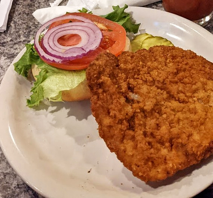 This breaded pork tenderloin sandwich is living its best life&mdash;crispy, oversized, and ready to make your regular burger feel completely inadequate.