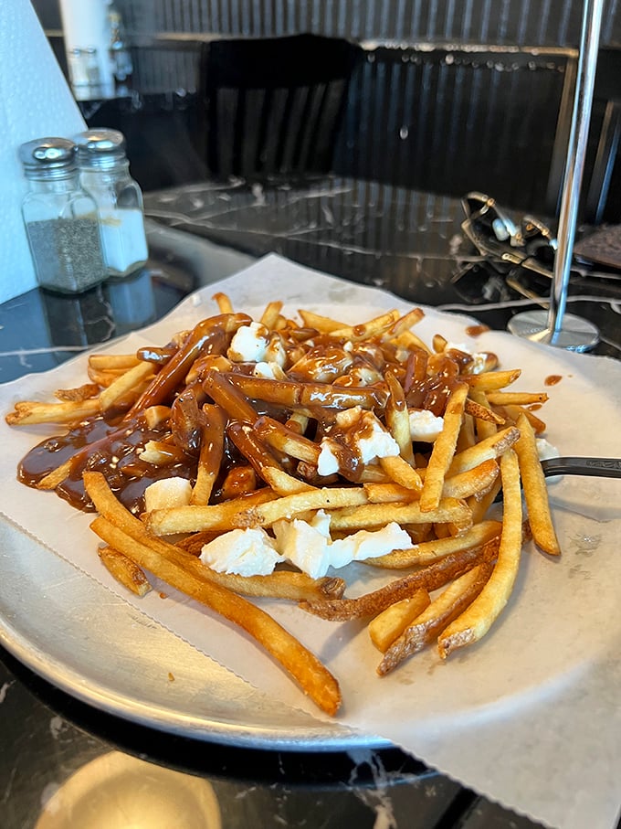 Poutine perfection: crispy fries smothered in savory gravy and dotted with cheese curds. Like a warm hug for your taste buds on a Virginia afternoon.