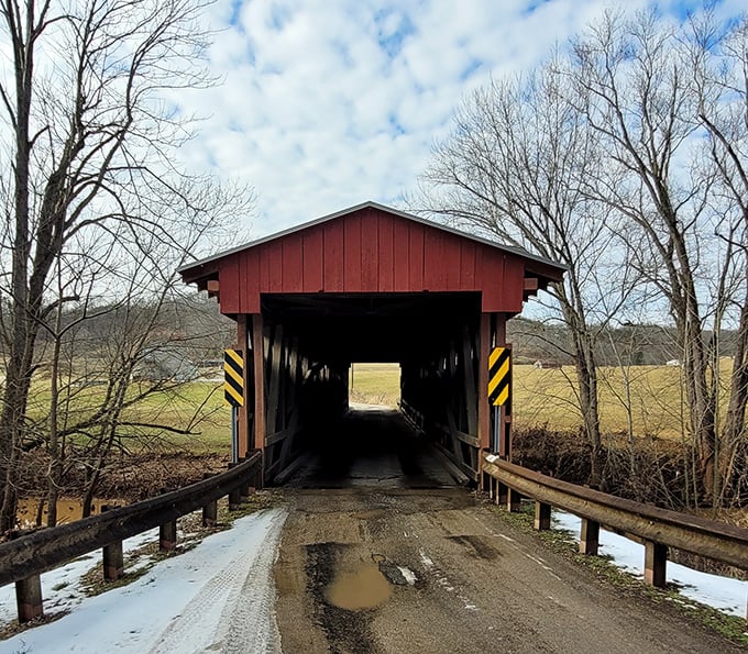 The bridge's weathered entrance beckons with muddy charm&mdash;a portal to simpler times when craftsmanship trumped convenience and haste.