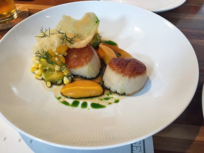 Perfectly seared scallops share the plate with vibrant vegetables and sauces in a dish that's equal parts science and sorcery.