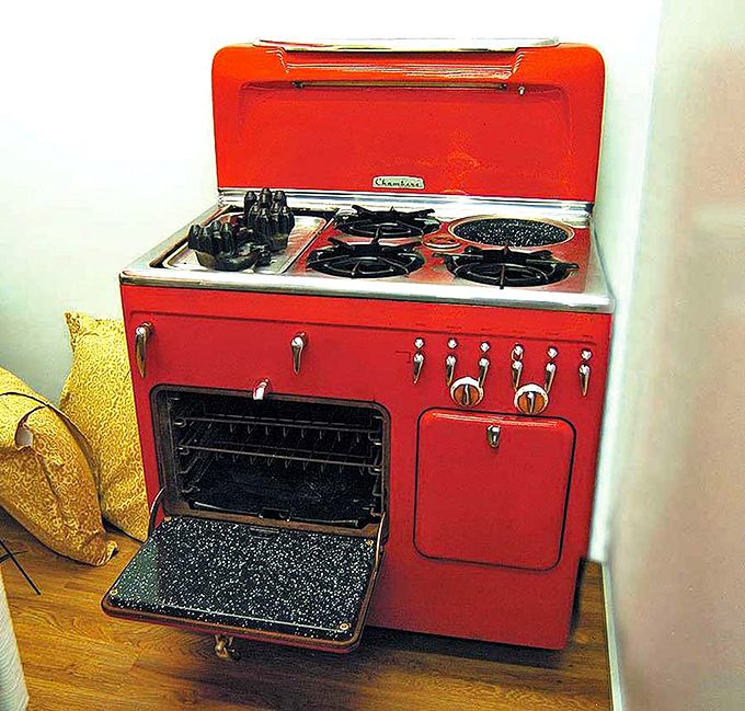 That cherry-red vintage stove is basically the kitchen equivalent of driving a classic convertible—pure style and substance.