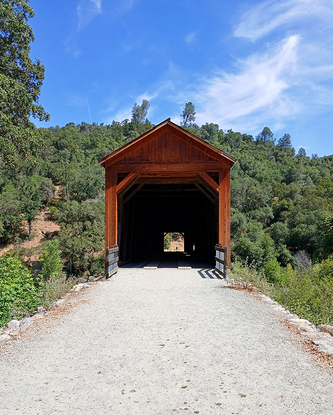 The bridge's entrance frames the path ahead like a portal to the past, its timber silhouette standing proud against California's azure skies.