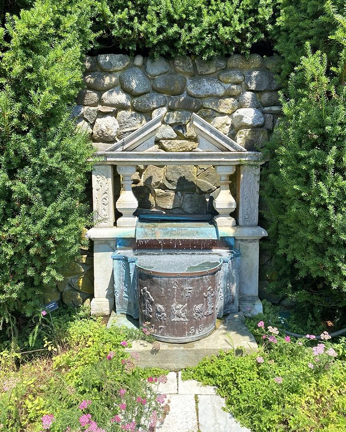 This fountain wears its weathered patina like a badge of honor, framed by evergreens standing at attention.