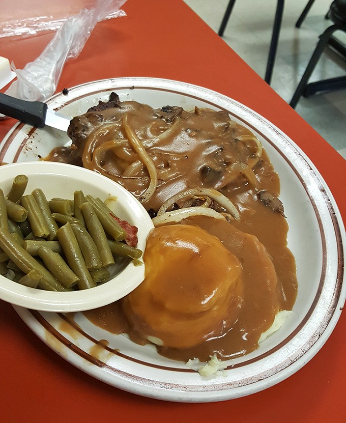 Gravy isn't just a condiment here; it's practically a food group, lovingly blanketing this hamburger steak like a warm West Virginia hug.