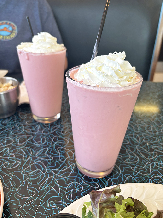 Strawberry milkshakes thick enough to require Olympic-level straw skills. The whipped cream hats aren't optional&mdash;they're essential architecture.