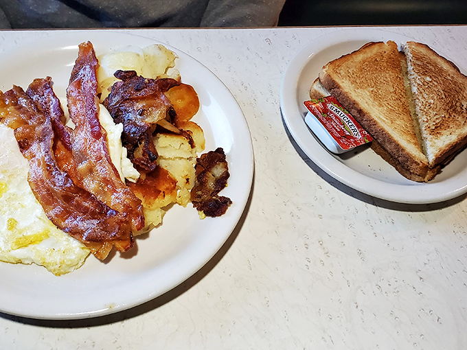 The breakfast trinity: perfectly crisp bacon, eggs cooked just right, and toast waiting patiently for its butter bath. Simple perfection.