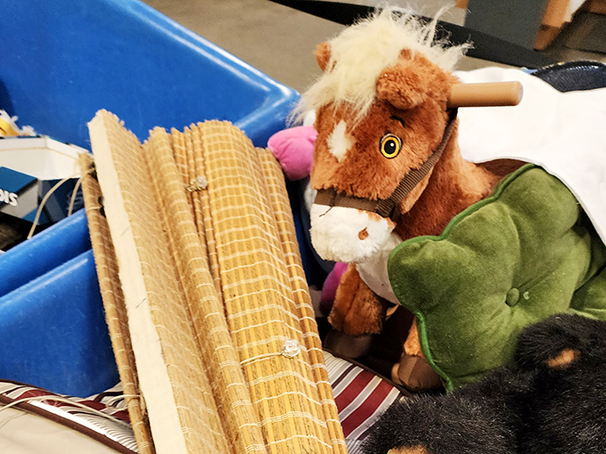 A stuffed horse peeks out from textile neighbors &ndash; one child's outgrown companion waiting for its next adventure with a new friend.