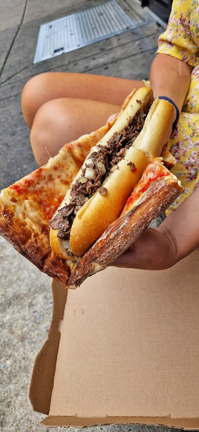 The ultimate Philadelphia power move: pizza in one hand, cheesesteak in the other. City of Brotherly Gluttony.
