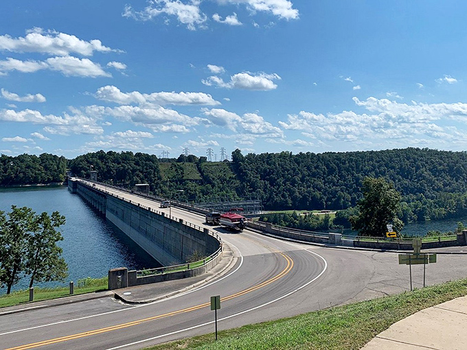 Bull Shoals Dam curves gracefully across crystal blue waters, where engineering marvel meets nature's splendor under an Arkansas sky dotted with cotton-candy clouds.