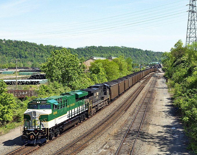 A freight train rolls through lush green surroundings near Duquesne, where the rhythm of rail traffic complements the affordable pace of retirement living.