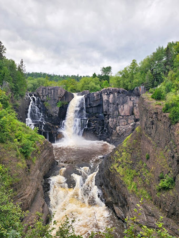 Grand Portage's High Falls thunders down in magnificent splendor, sending up mist that feels like nature's own air conditioning.