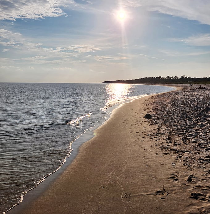 Golden hour magic transforms this quiet shoreline into nature's light show. Footprints in the sand tell stories of perfect beach days.
