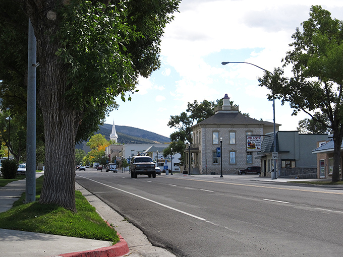 A quiet stretch of main street showcases Manti&rsquo;s small-town charm, with historic stone buildings and a distant church steeple framed by rolling hills.