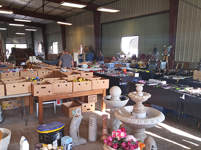 Treasure hunting paradise! Cardboard boxes brimming with colorful odds and ends sit beside elegant garden fountains &ndash; the perfect flea market contrast of humble and grand.