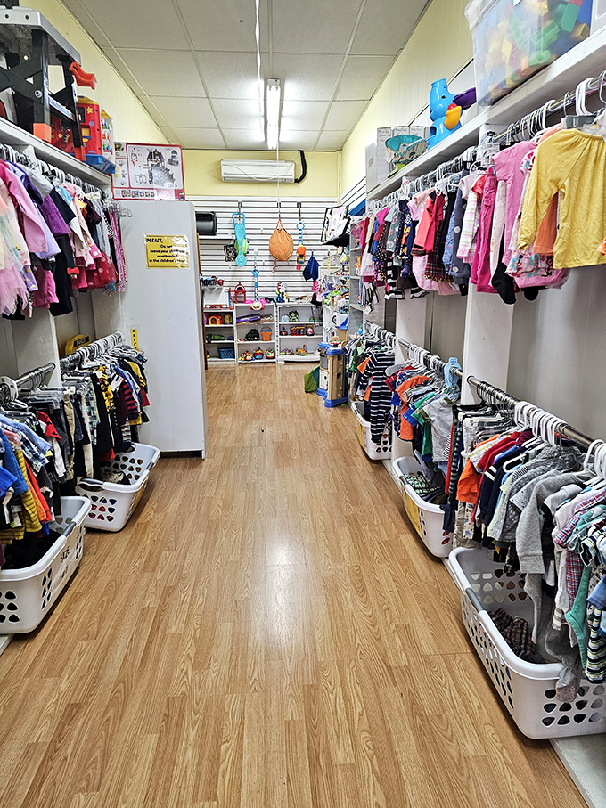 A narrow aisle packed with children's clothing &ndash; tiny treasures organized with care for budget-conscious parents.