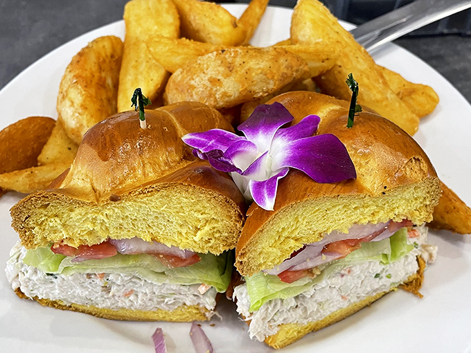 A sandwich that brings California sunshine to Florida plates—creamy avocado, fresh veggies, and chicken salad on a golden bagel with those legendary home fries.