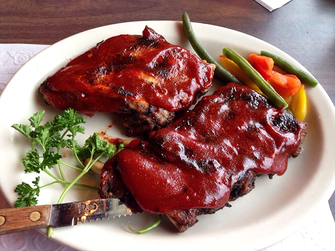 These baby back ribs wear their sauce like a glossy coat of armor, protecting the tender meat beneath until your fork declares war.