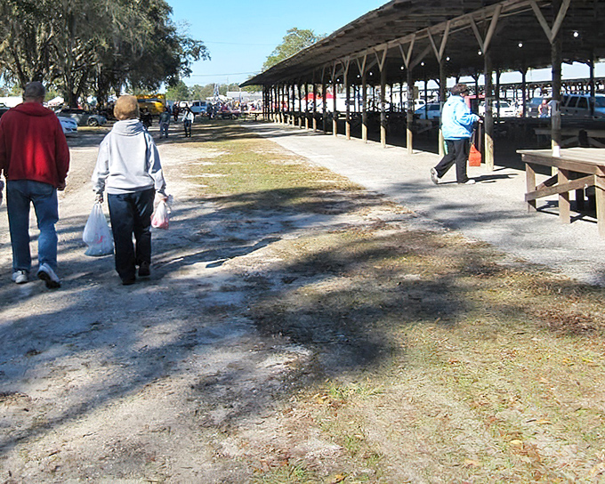 Early birds catch the deals. Shoppers with white bags have already scored their finds while others head toward the covered pavilion for more discoveries. 