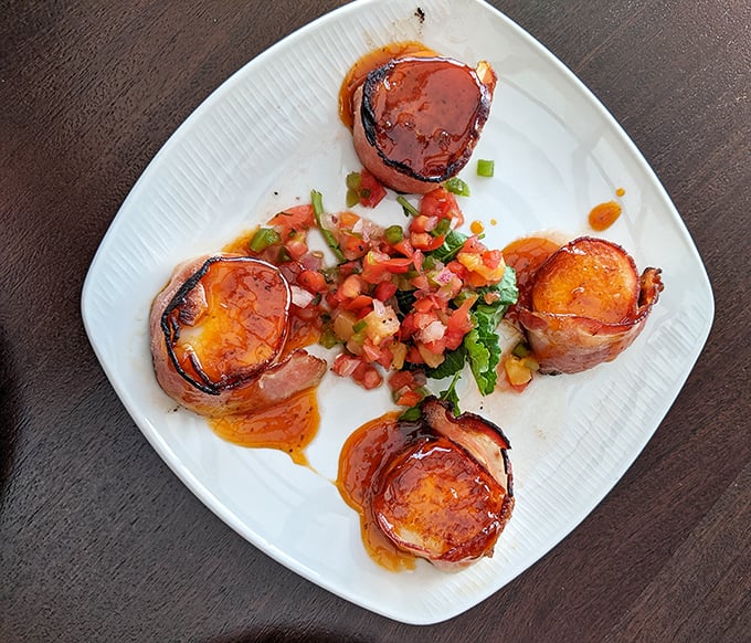 Bacon-wrapped scallops: where land meets sea in perfect harmony. That fresh salsa in the middle isn't just garnish&mdash;it's the referee.